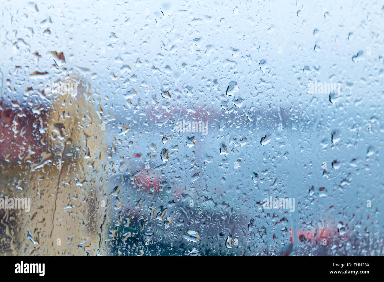 Blue rainy background, flowing down water drops on the window glass ...
