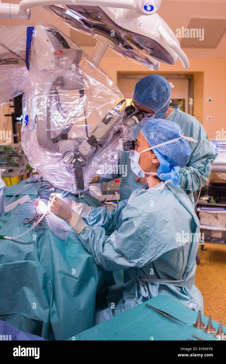 Surgeon performing cochlear implant surgery, an operation involving the ...