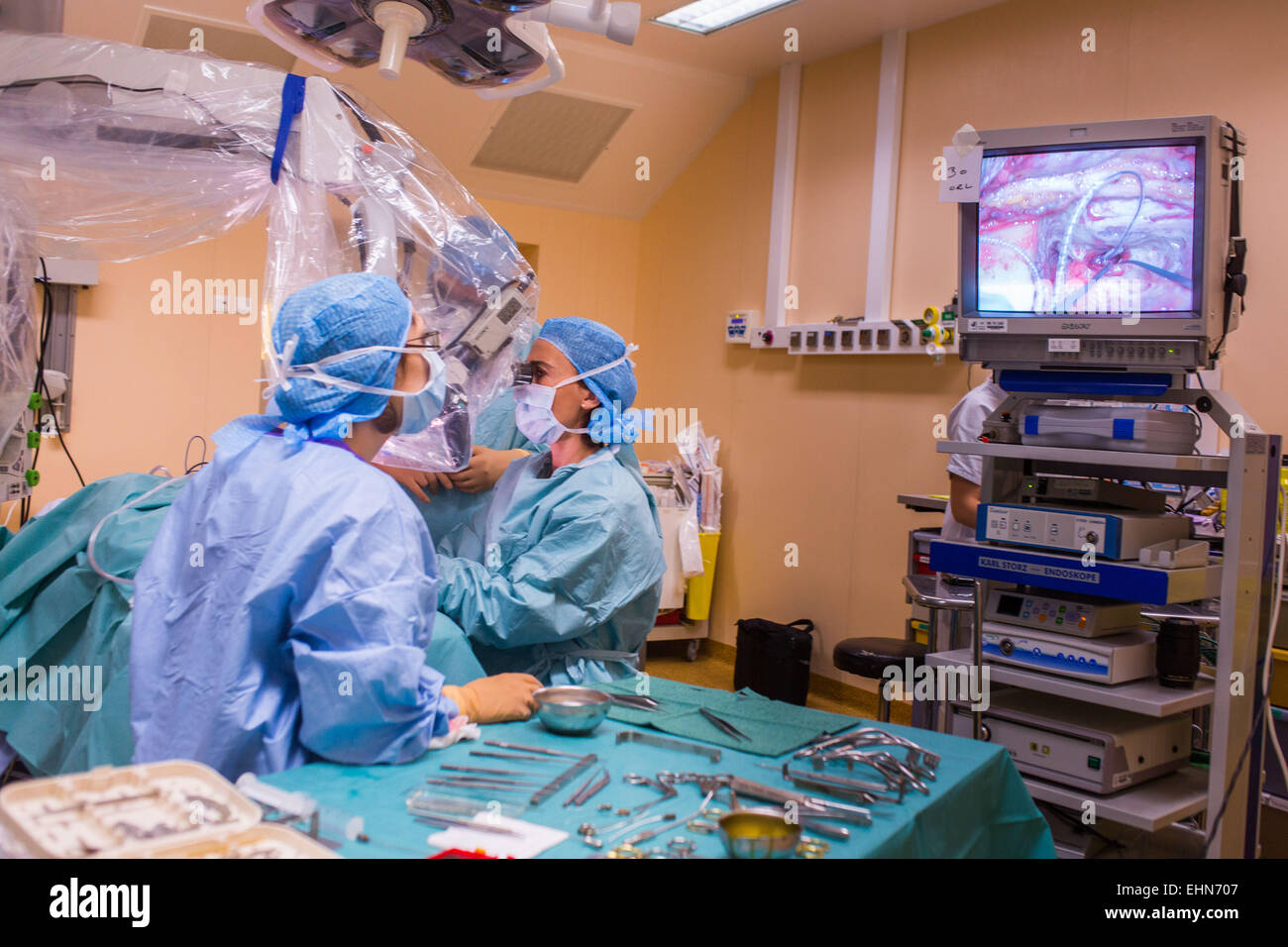 Surgeon performing cochlear implant surgery, an operation involving the ...
