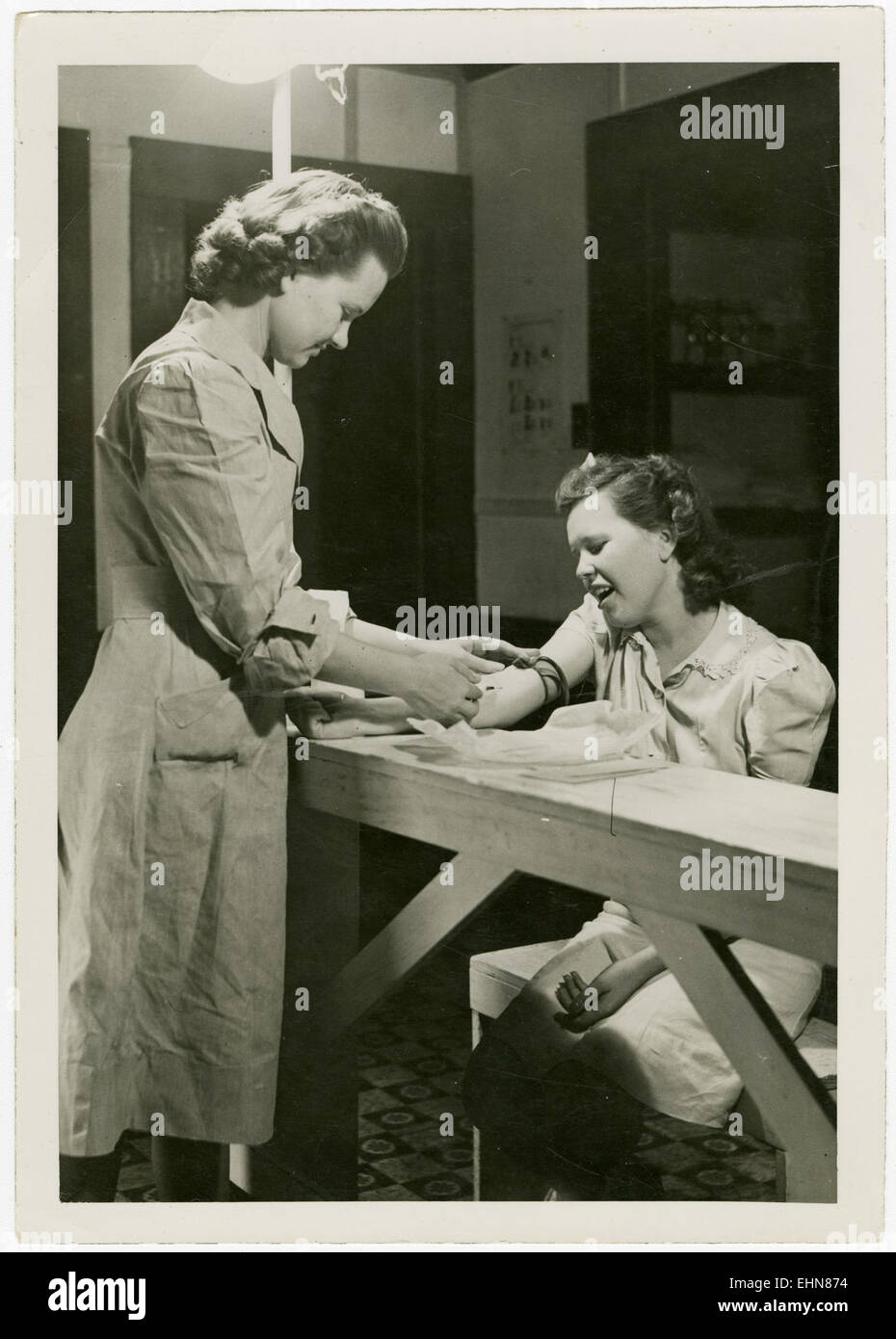 This 1940s photograph captures a nurse and a young woman seated at a ...