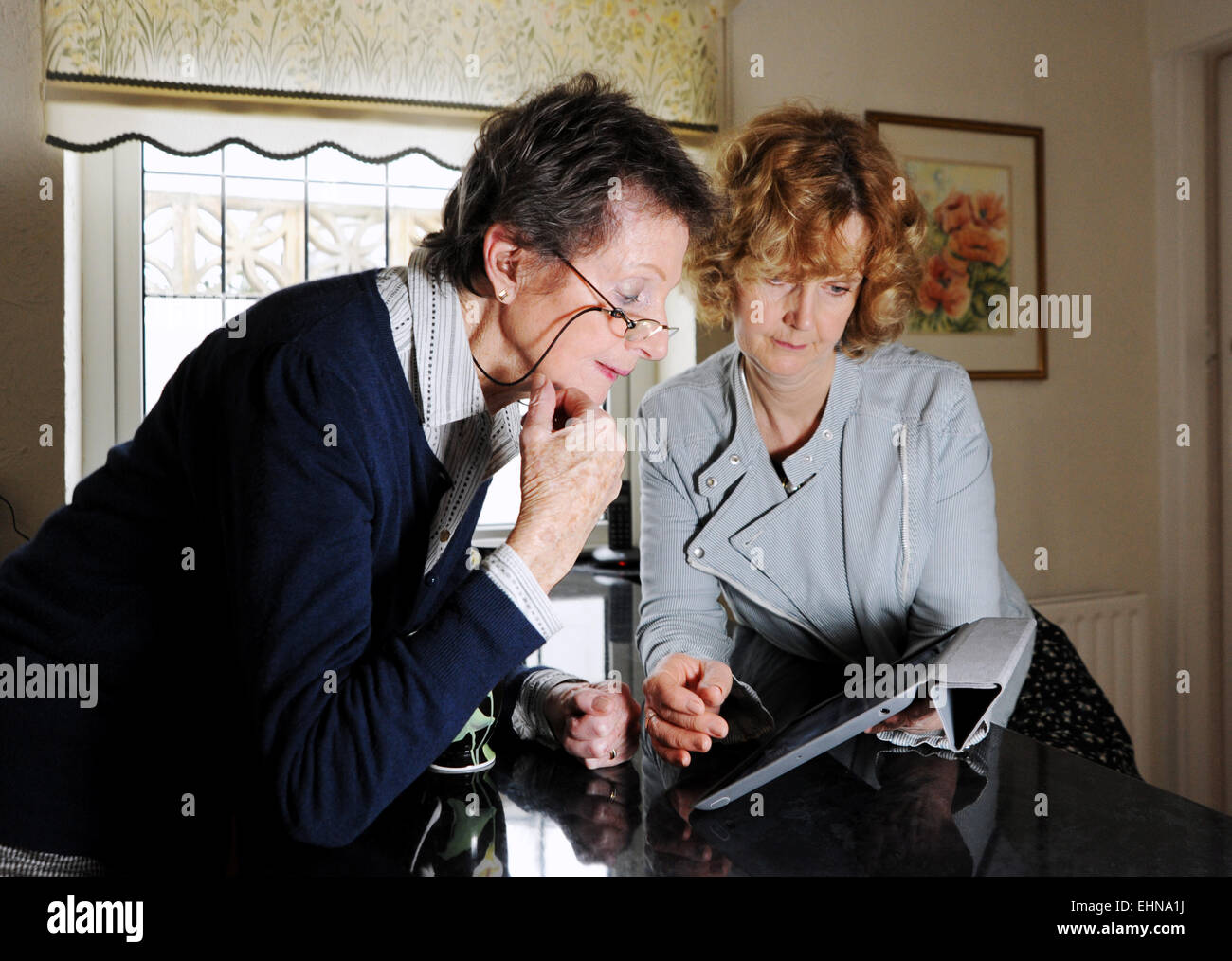 Old age pensioner female and younger woman using an Apple iPad tablet ...