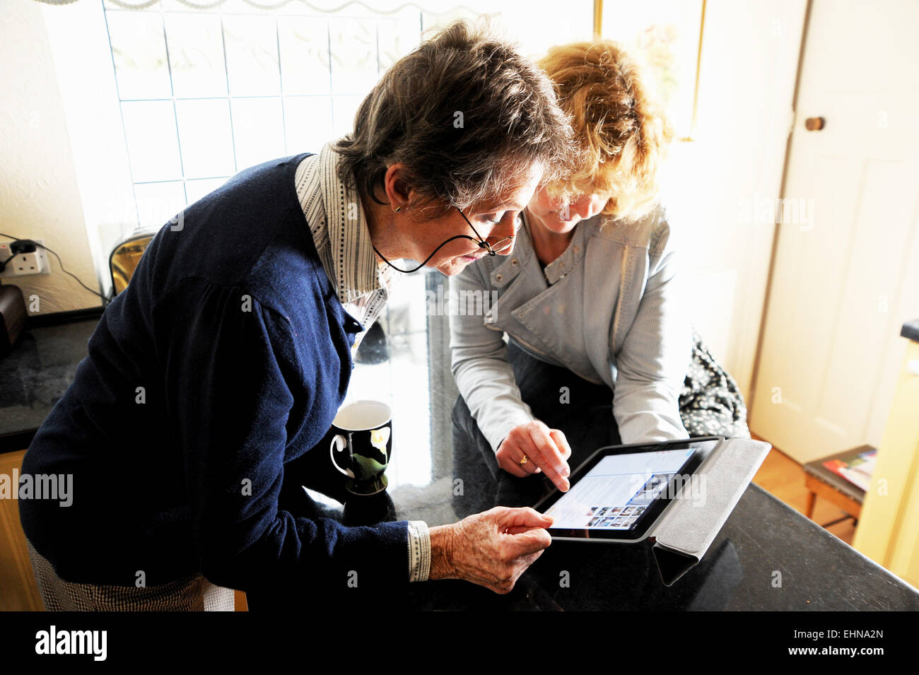 Old age pensioner female and younger woman using an Apple iPad tablet ...