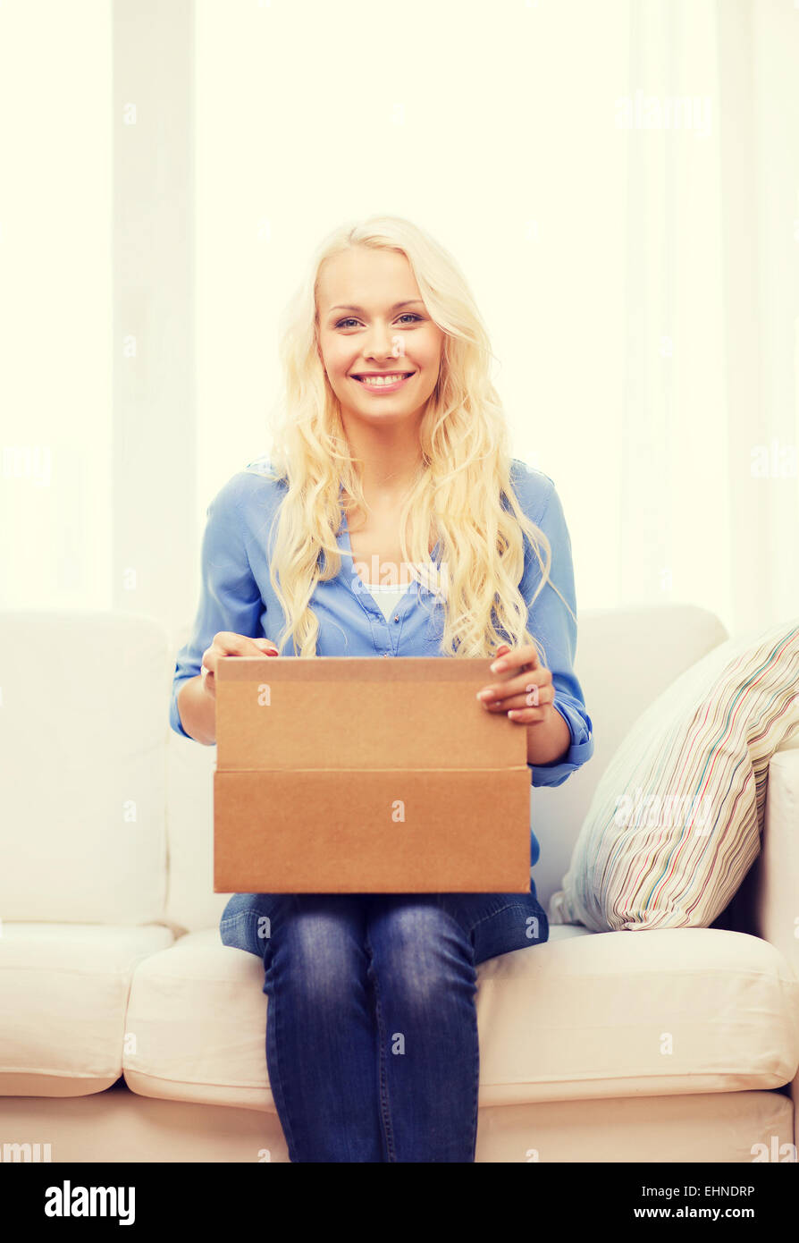 smiling young woman opening cardboard box Stock Photo - Alamy