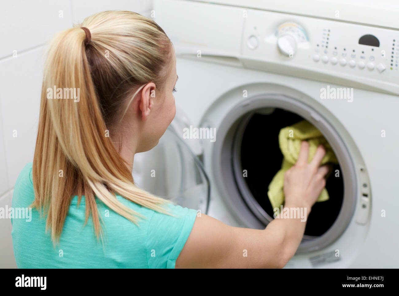 happy woman putting laundry into washer at home Stock Photo - Alamy