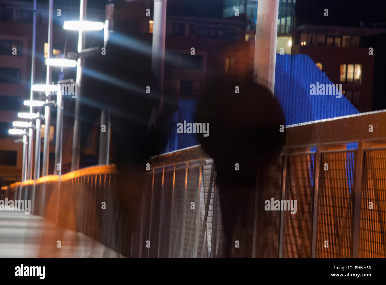 Two men walking over a pedestrian bridge at night Stock Photo - Alamy