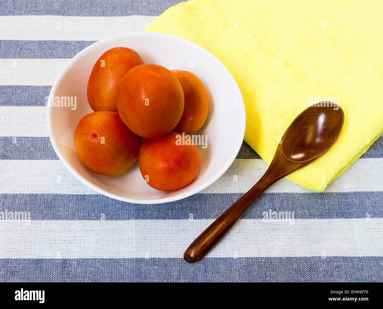 Wooden Spoon with White Bowl with Five Tomatoes Placed on Yellow Cloth ...