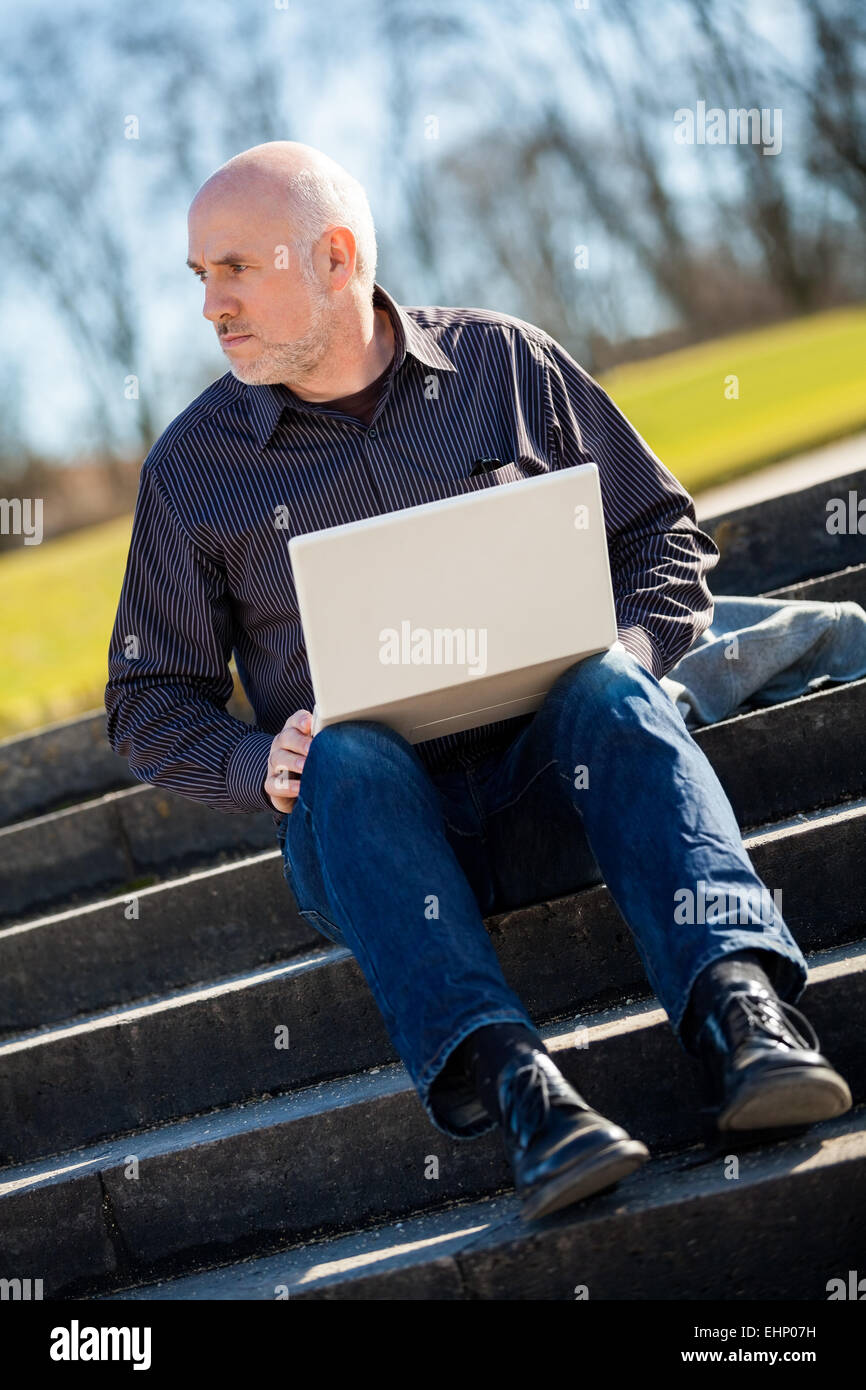 High angle profile view of a balding middle-aged man sitting on a ...