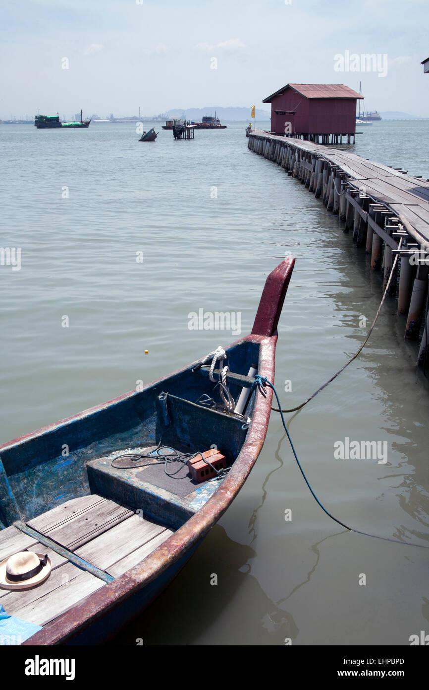 Wooden rowing boat with a straw hat next to a narrow wooden walkway ...