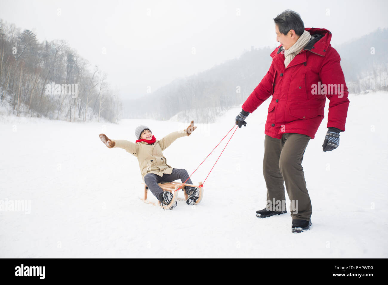 Grandfather pulling grandson on sled Stock Photo - Alamy