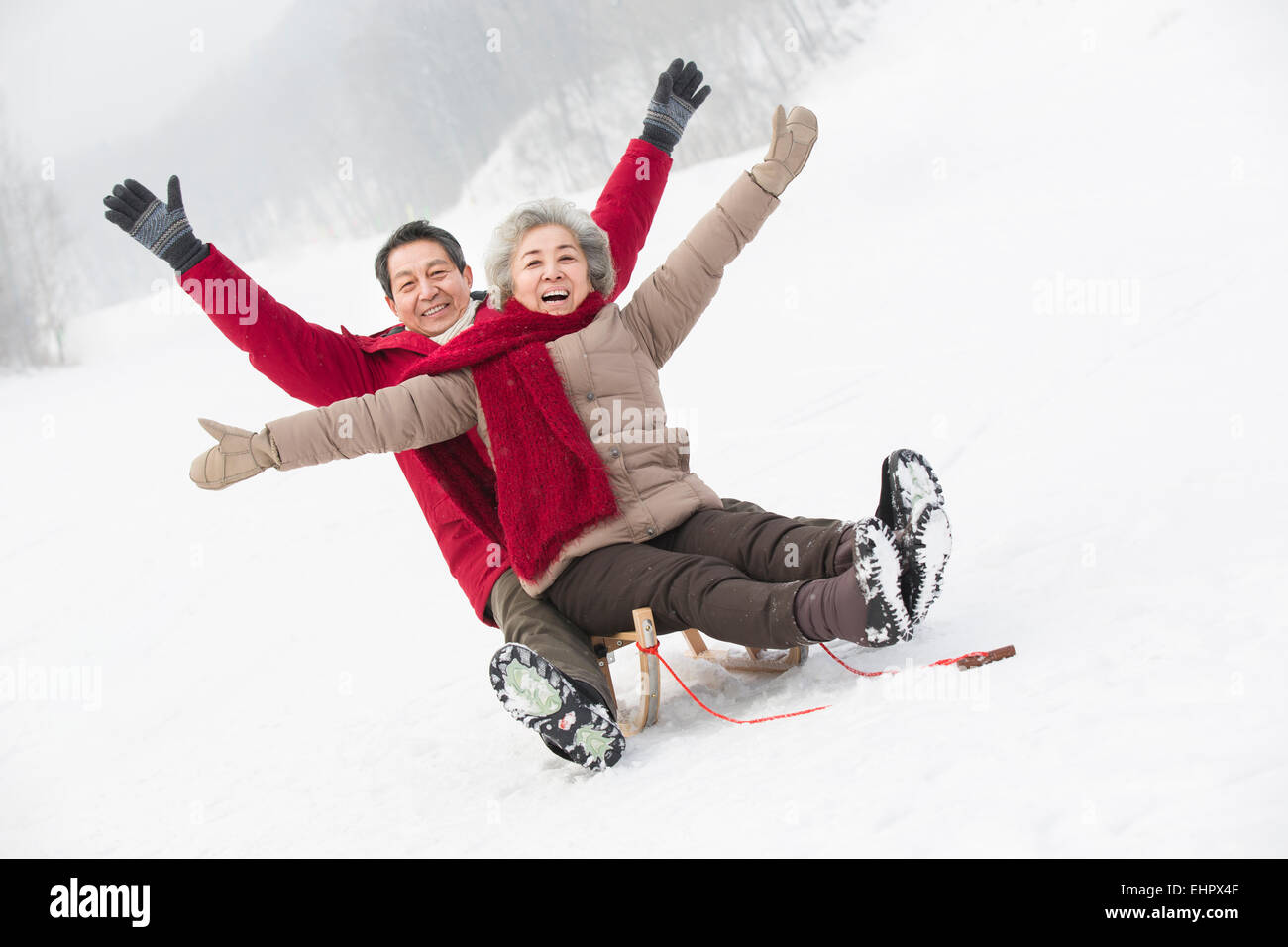 Happy senior couple sliding on a sled Stock Photo - Alamy