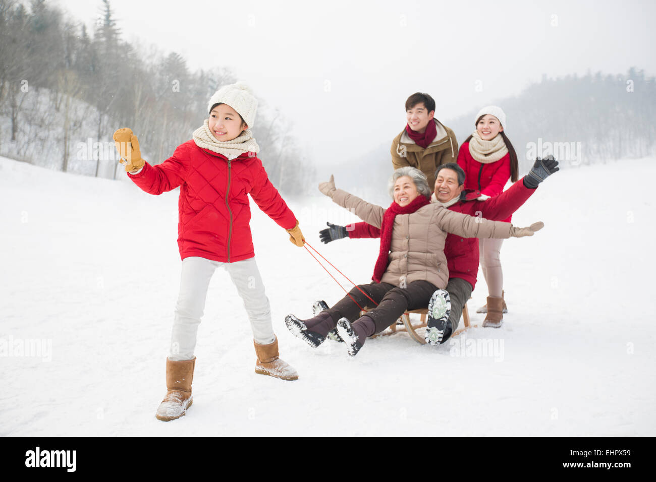 Happy family playing with sled on the snow Stock Photo - Alamy