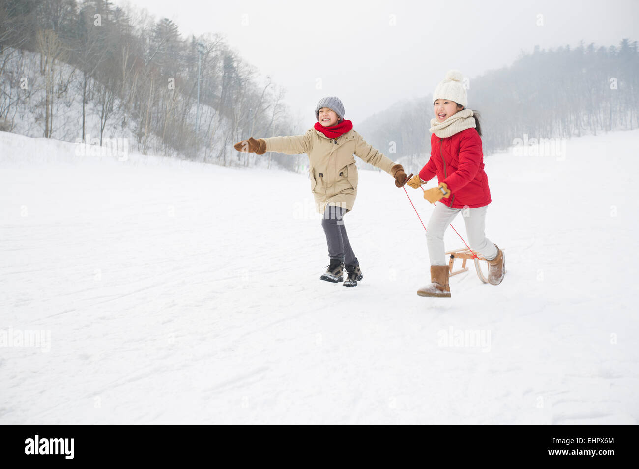 Happy children running with sled on the snow Stock Photo - Alamy