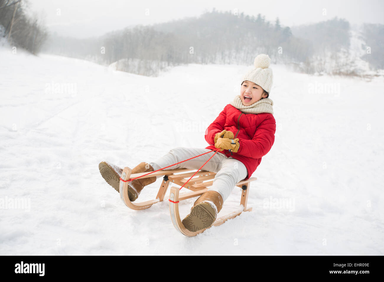 Happy girl sliding on a sled Stock Photo - Alamy