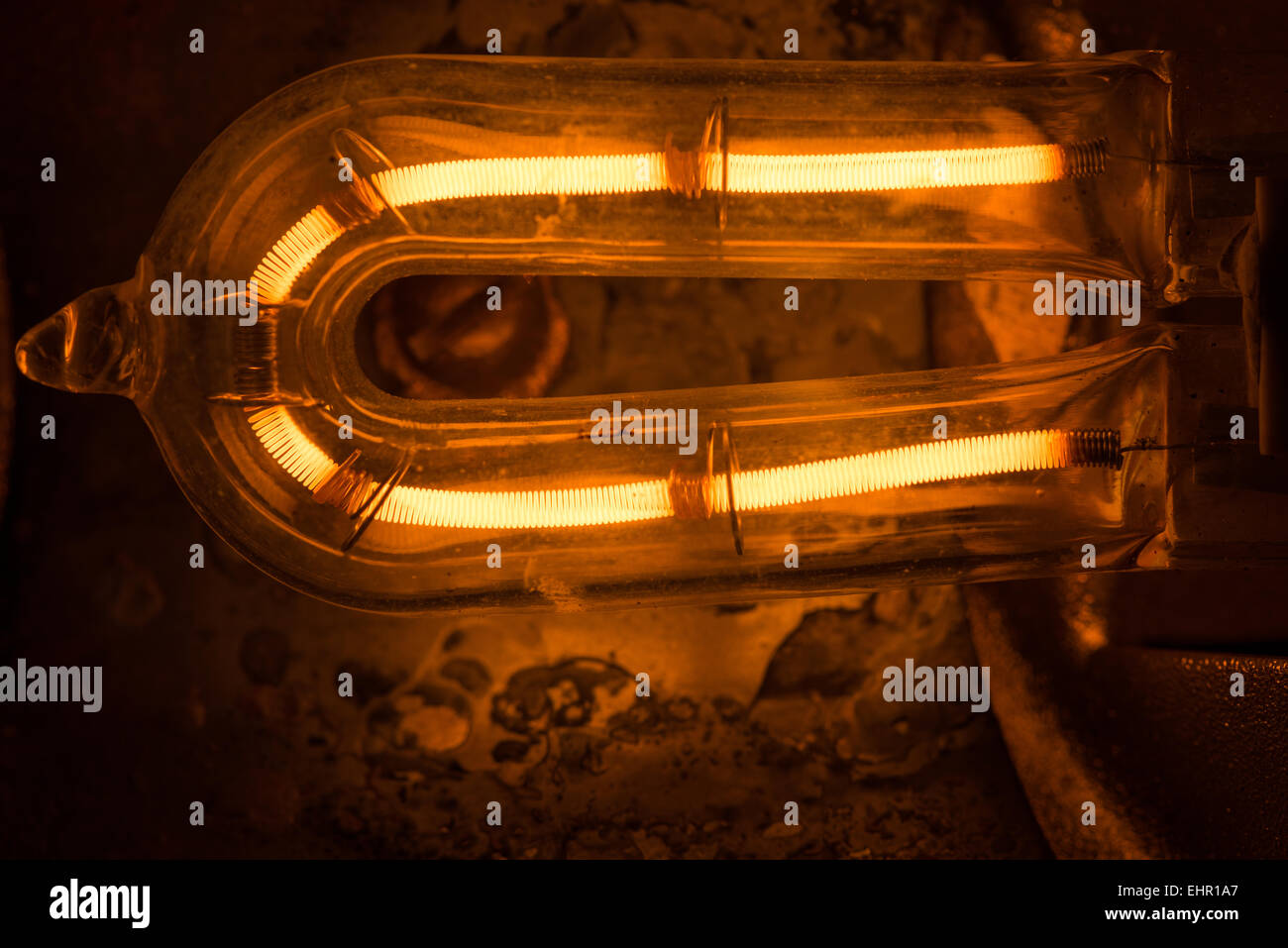 glowing filament of a 1000 quartz halogen bulb with flaked metal and ...