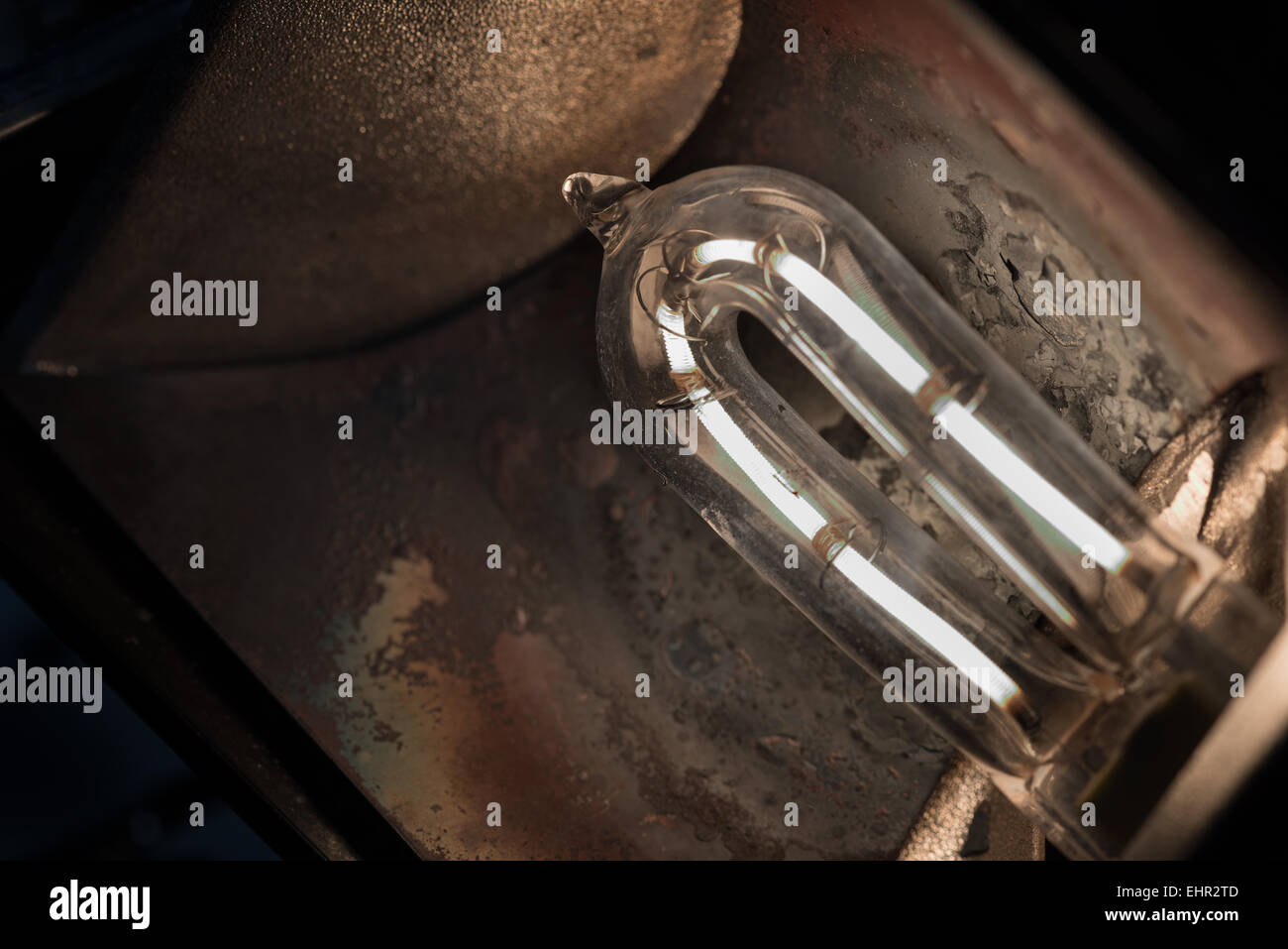 glowing filament of a 1000 quartz halogen bulb with flaked metal and ...