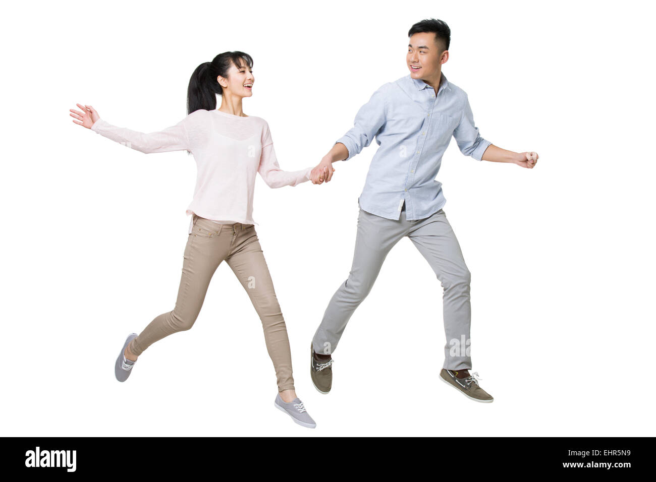 Happy young couple holding hands running Stock Photo - Alamy