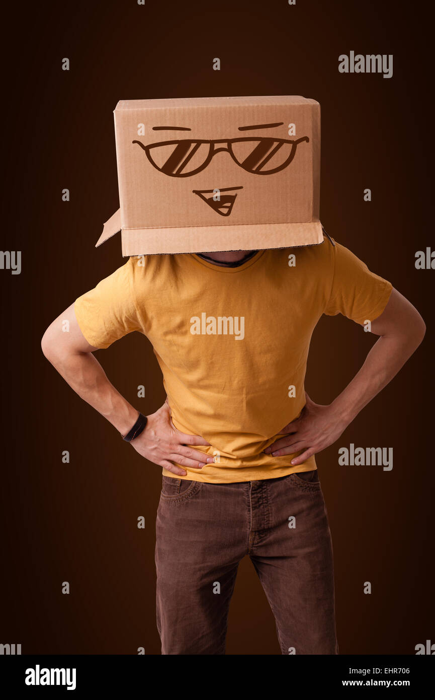 Young man gesturing with a cardboard box on his head with smiley face ...