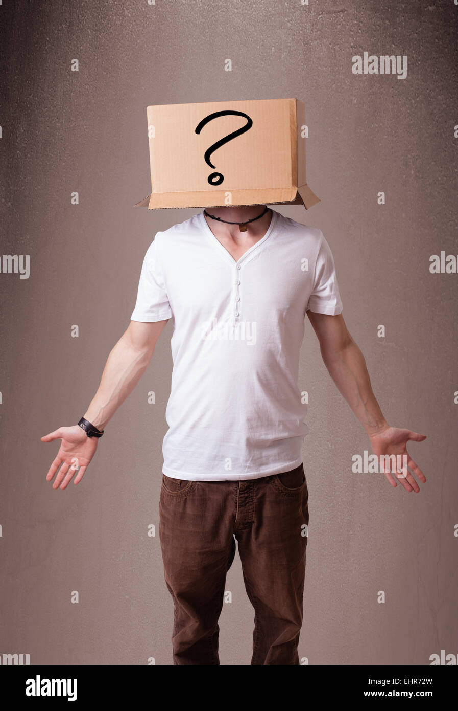 Young man gesturing with a cardboard box on his head with question mark ...