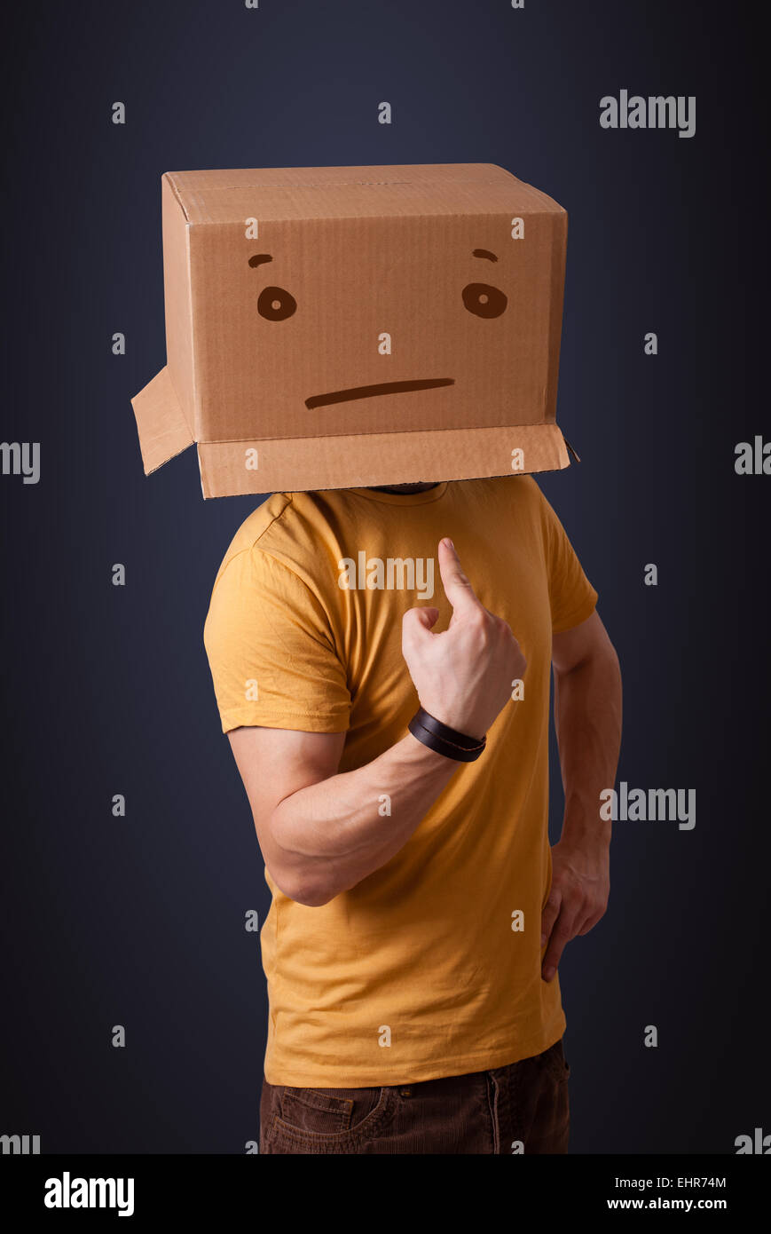 Young man gesturing with a cardboard box on his head with straight face ...