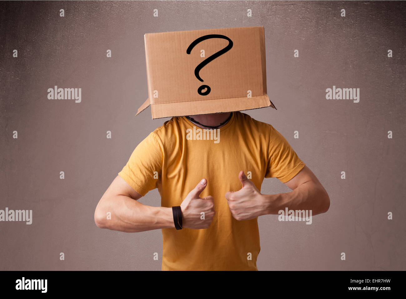 Young man gesturing with a cardboard box on his head with question mark ...