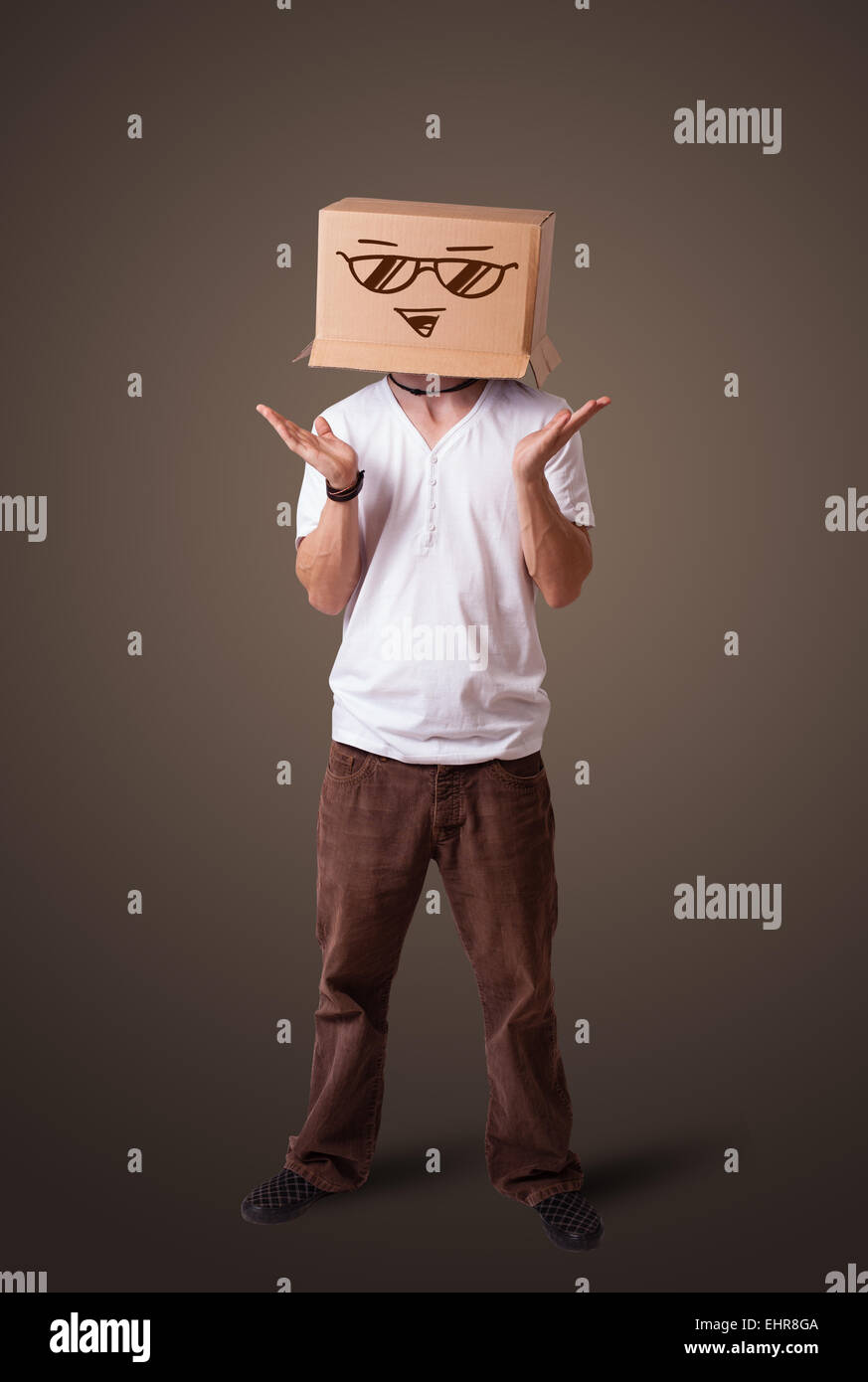Young man gesturing with a cardboard box on his head with smiley face ...
