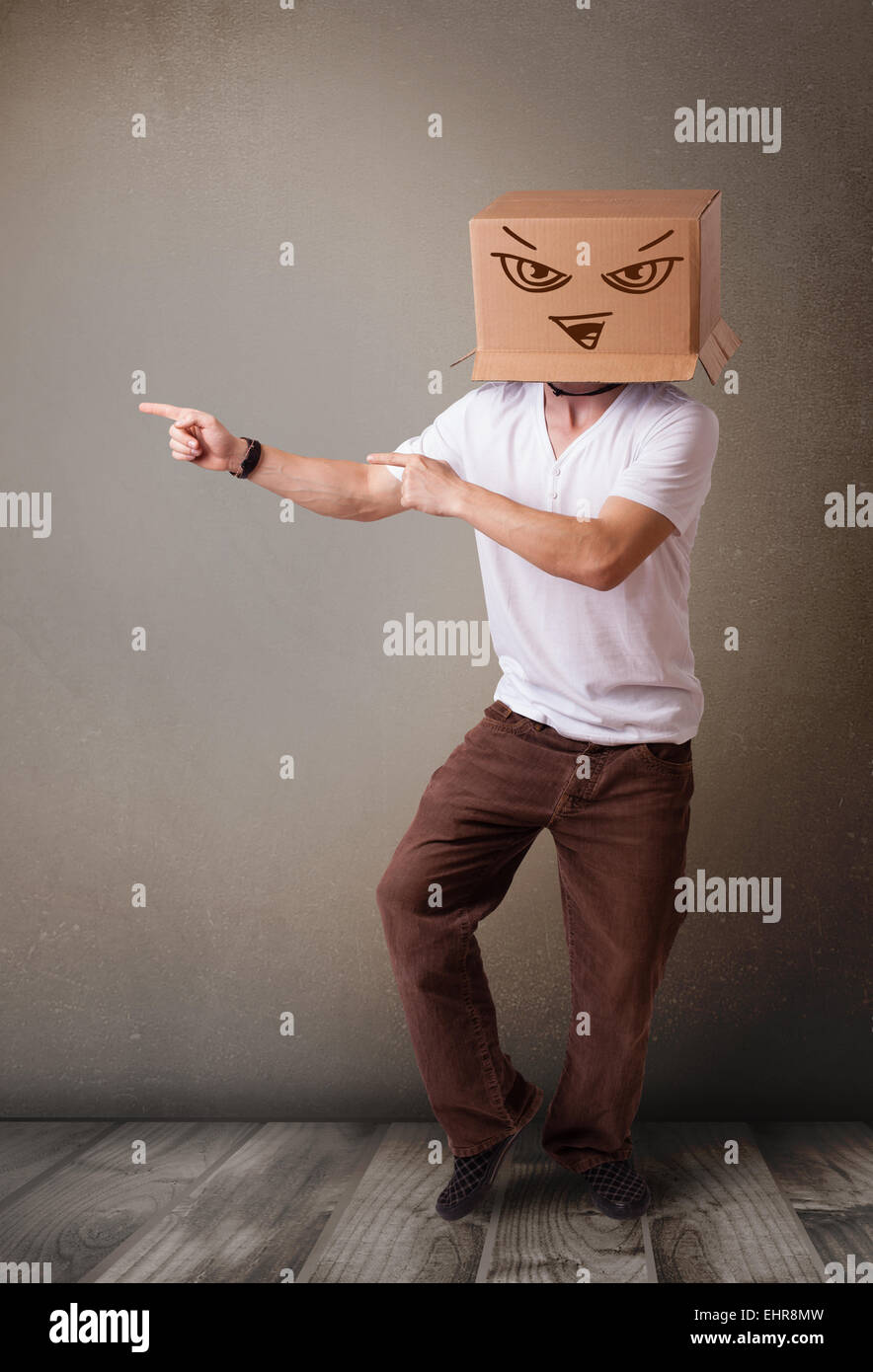 Young man gesturing with a cardboard box on his head with evil face ...