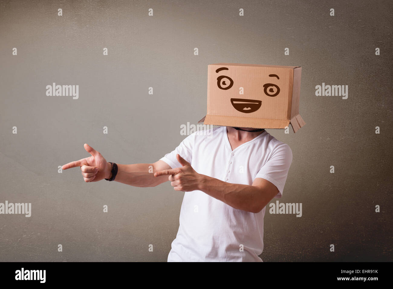 Young man gesturing with a cardboard box on his head with smiley face ...