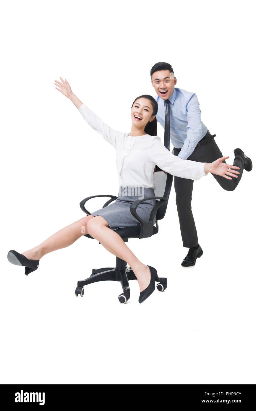 Businessman pushing businesswoman in rolling office chair Stock Photo ...