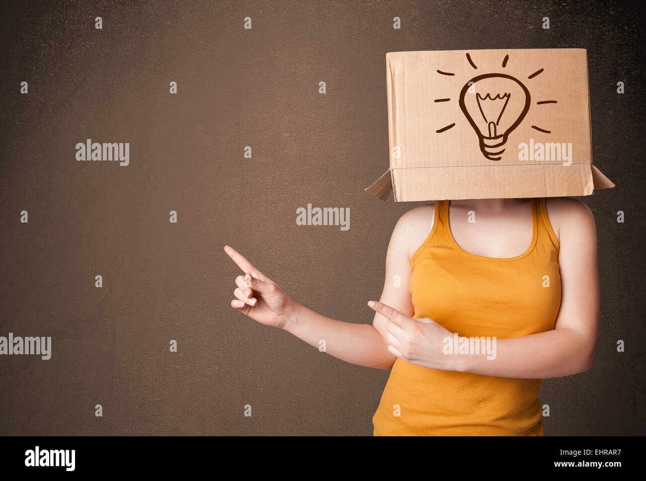 Young woman gesturing with a cardboard box on her head with light bulb ...