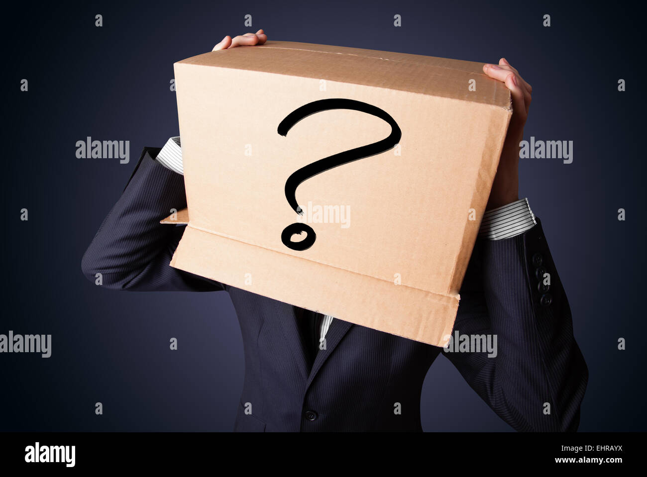 Businessman gesturing with a cardboard box on his head with question ...