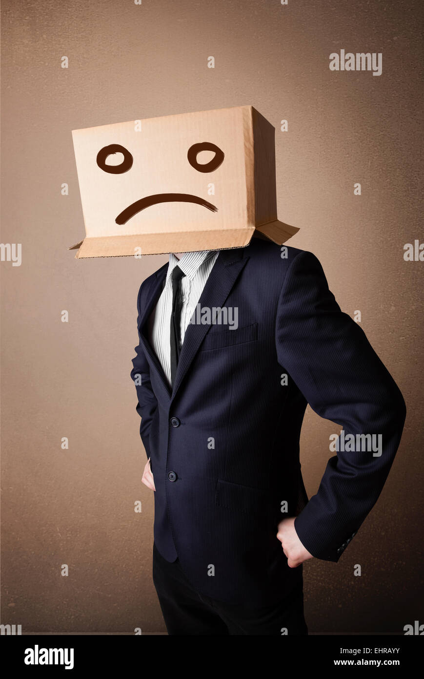 Businessman gesturing with cardboard box on his head with sad face ...