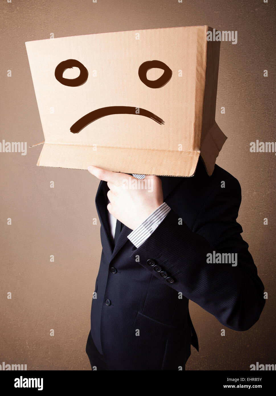 Businessman gesturing with cardboard box on his head with sad face ...