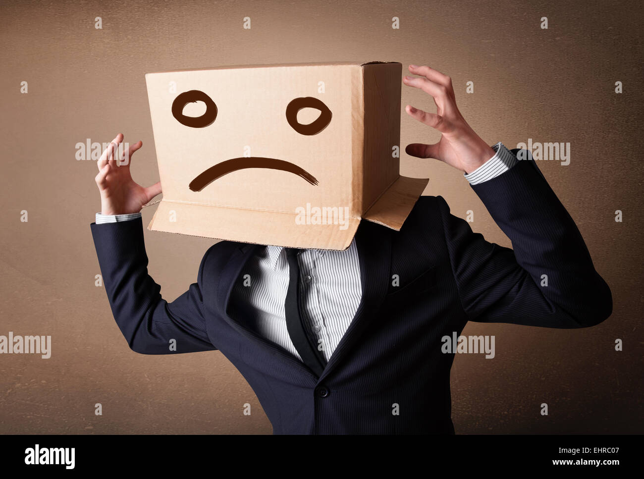 Businessman gesturing with cardboard box on his head with sad face ...