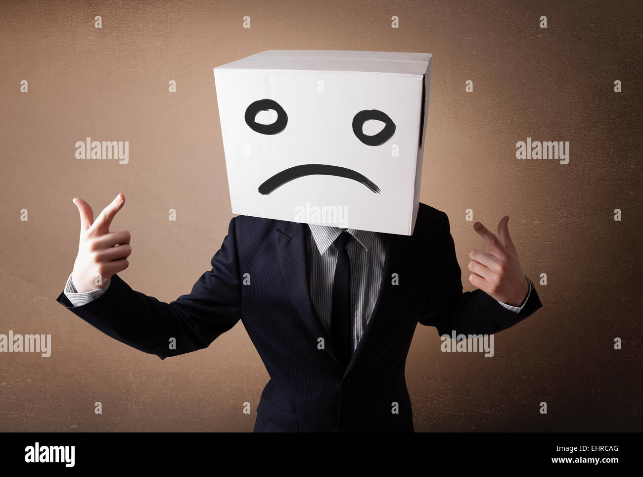 Businessman gesturing with cardboard box on his head with sad face ...