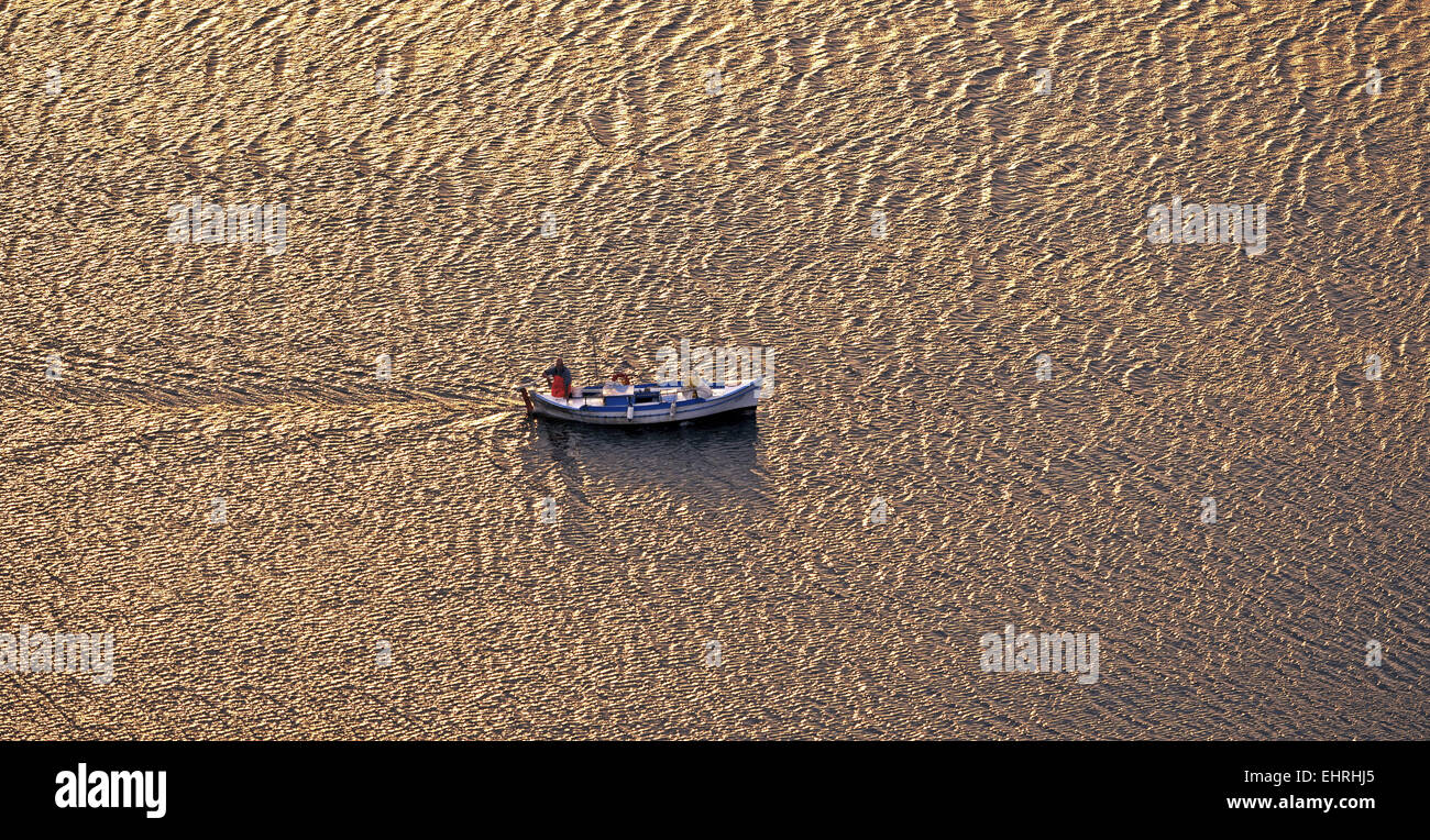 Caique (traditional fishing boat) sets out at sunset in the north Evian ...