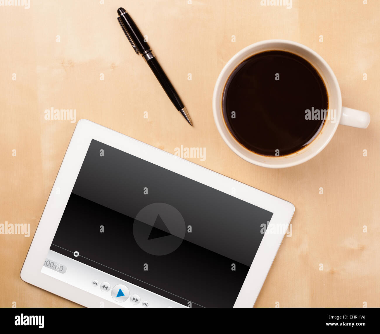 Tablet pc showing media player on screen with a cup of coffee on a desk ...