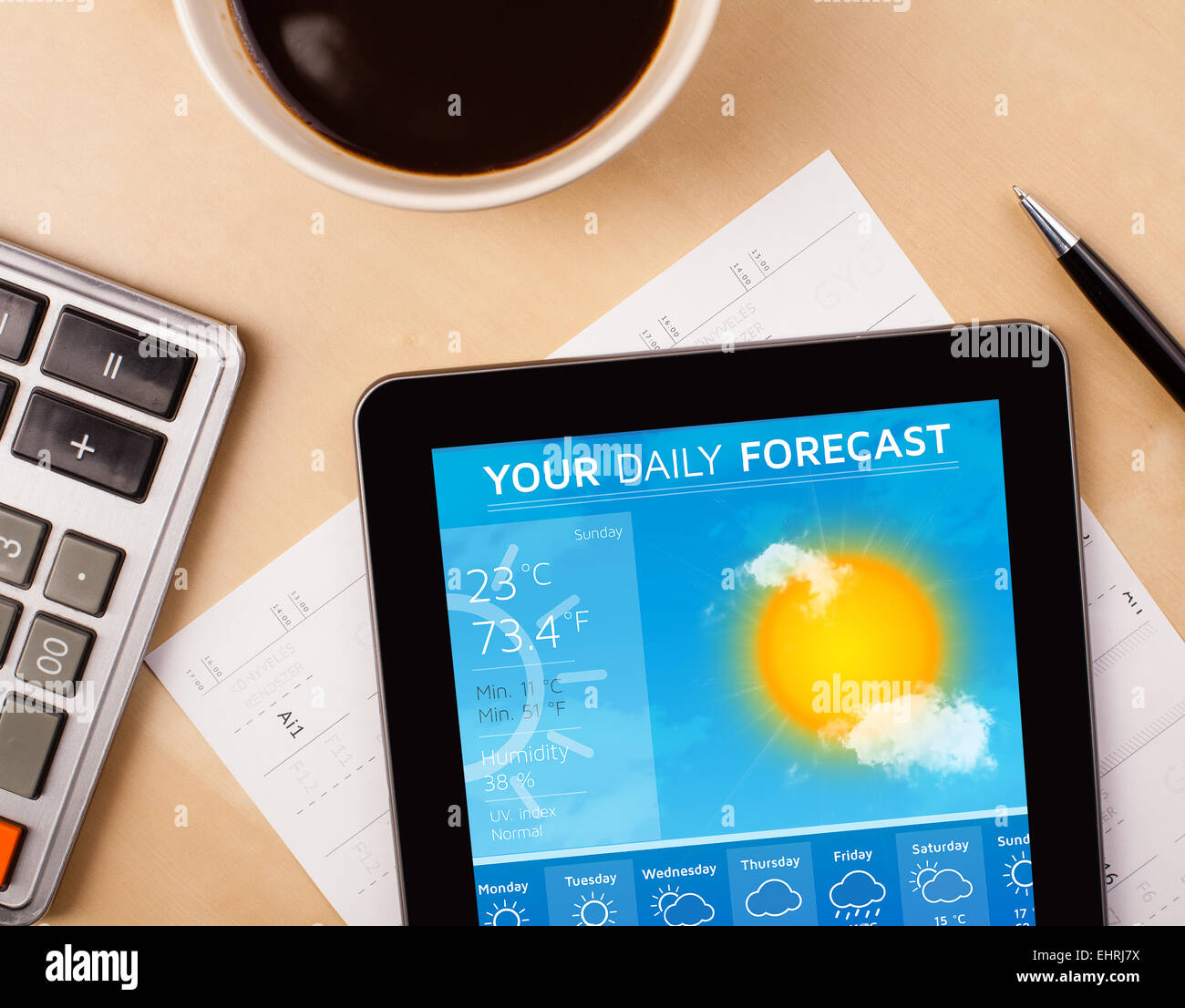 Tablet pc showing weather forecast on screen with a cup of coffee on a ...