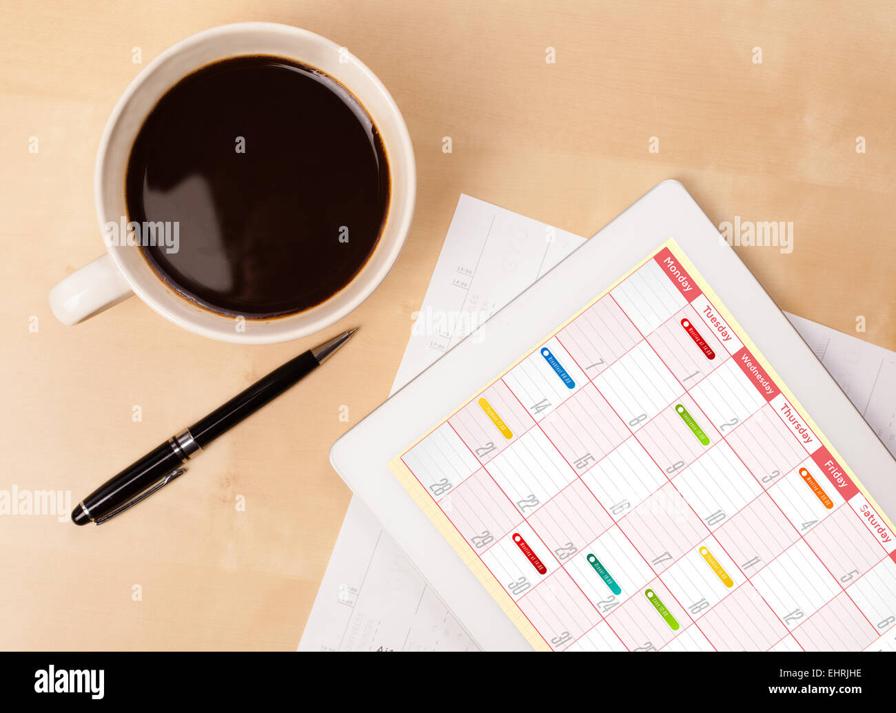 Tablet pc showing calendar on screen with a cup of coffee on a desk ...