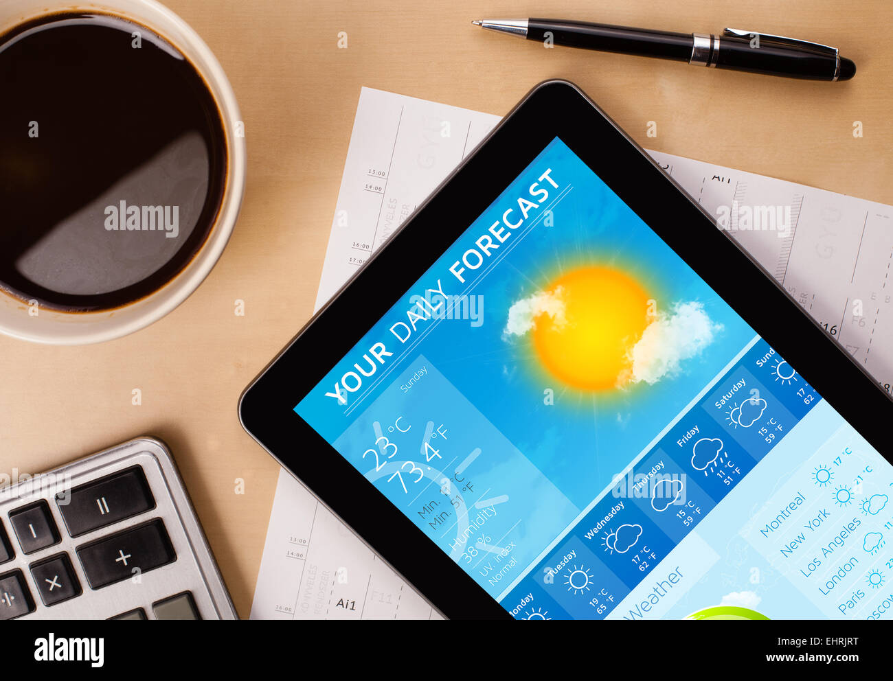 Tablet pc showing weather forecast on screen with a cup of coffee on a ...