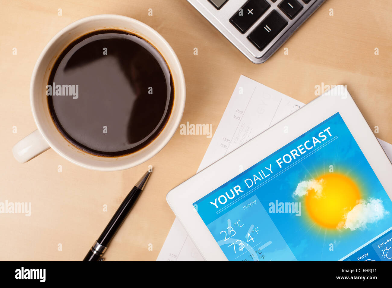 Tablet pc showing weather forecast on screen with a cup of coffee on a ...