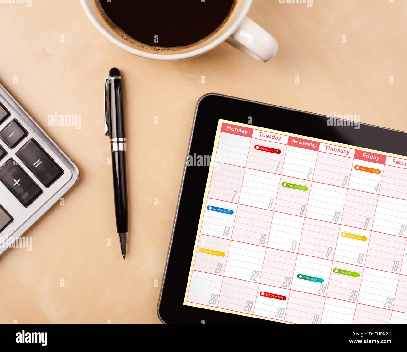 Tablet pc showing calendar on screen with a cup of coffee on a desk ...