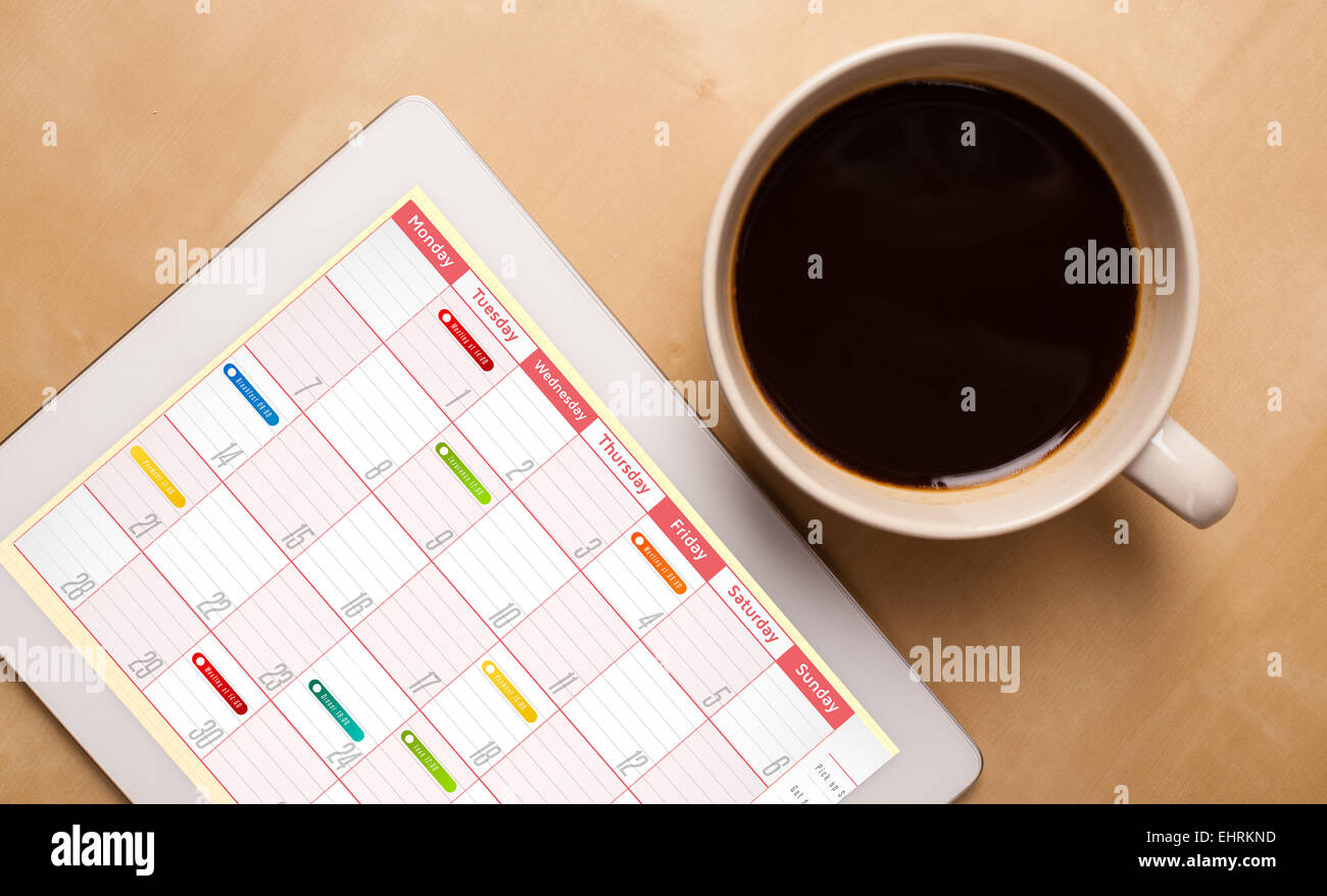 Tablet pc showing calendar on screen with a cup of coffee on a desk ...