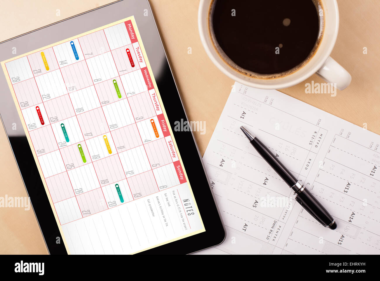 Tablet pc showing calendar on screen with a cup of coffee on a desk ...