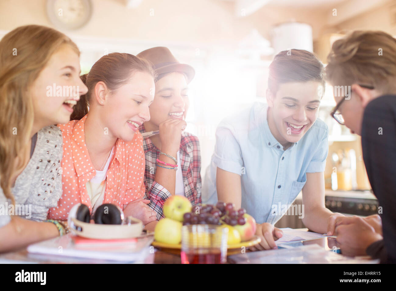 Group of smiling teenagers gathered around table in dining room Stock ...