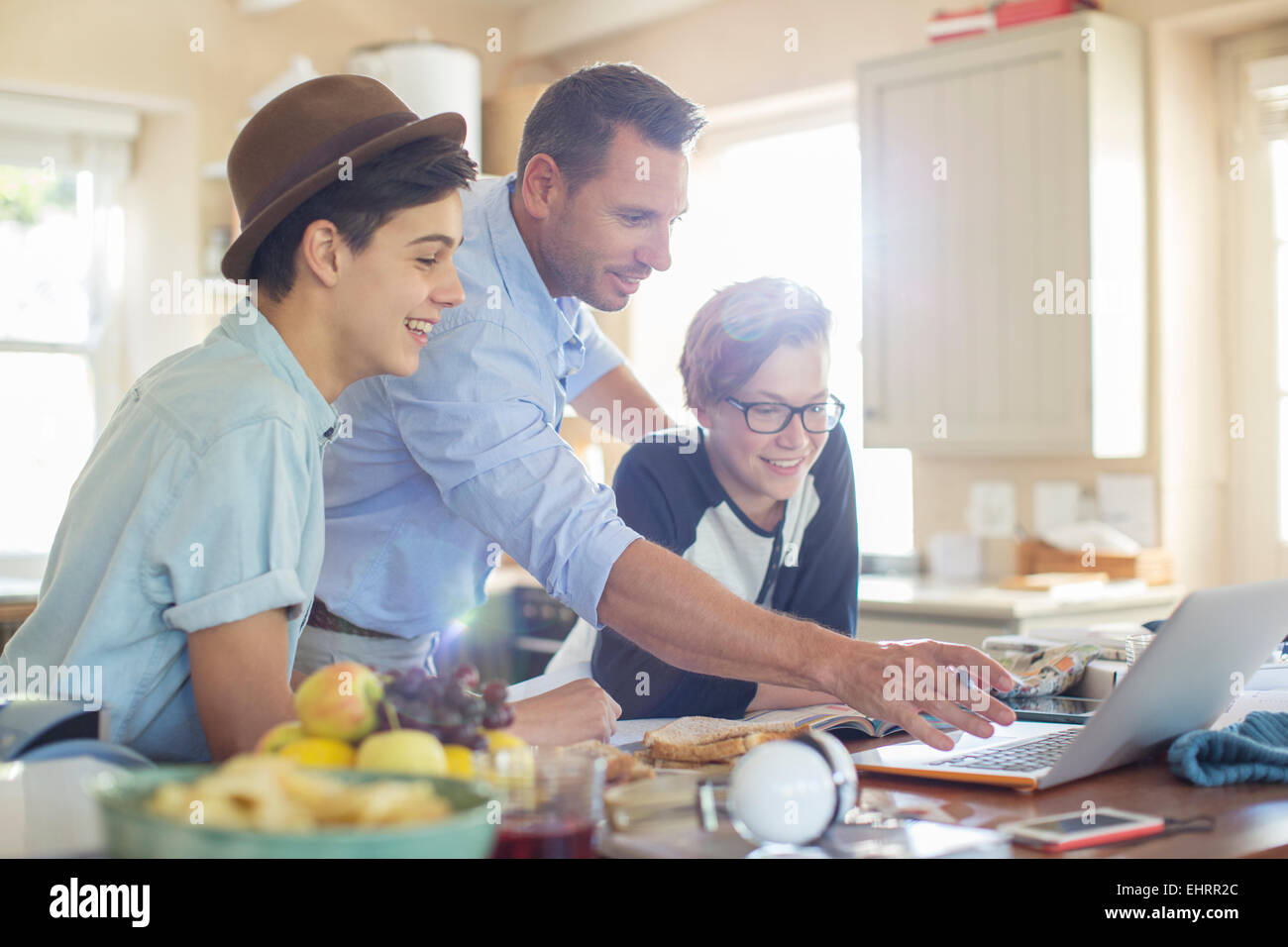 Mid adult man with teenage boys using laptop in kitchen Stock Photo - Alamy