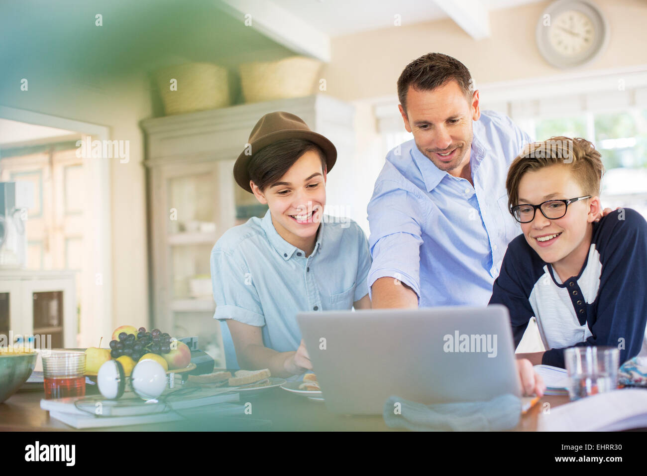 Mid adult man with teenage boys using laptop in kitchen Stock Photo - Alamy