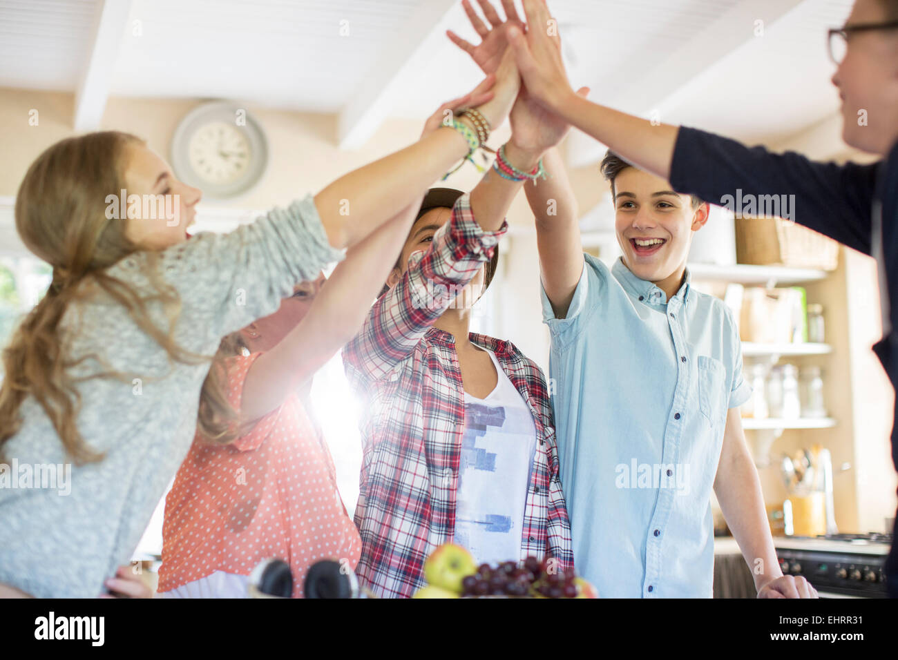Group of teenagers doing high five in living room Stock Photo - Alamy