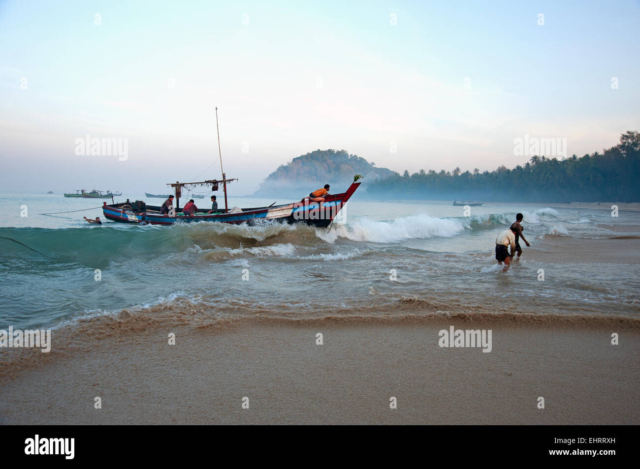 A fishing boat moors at dawn on the sandy beach at Ngapali beach ...