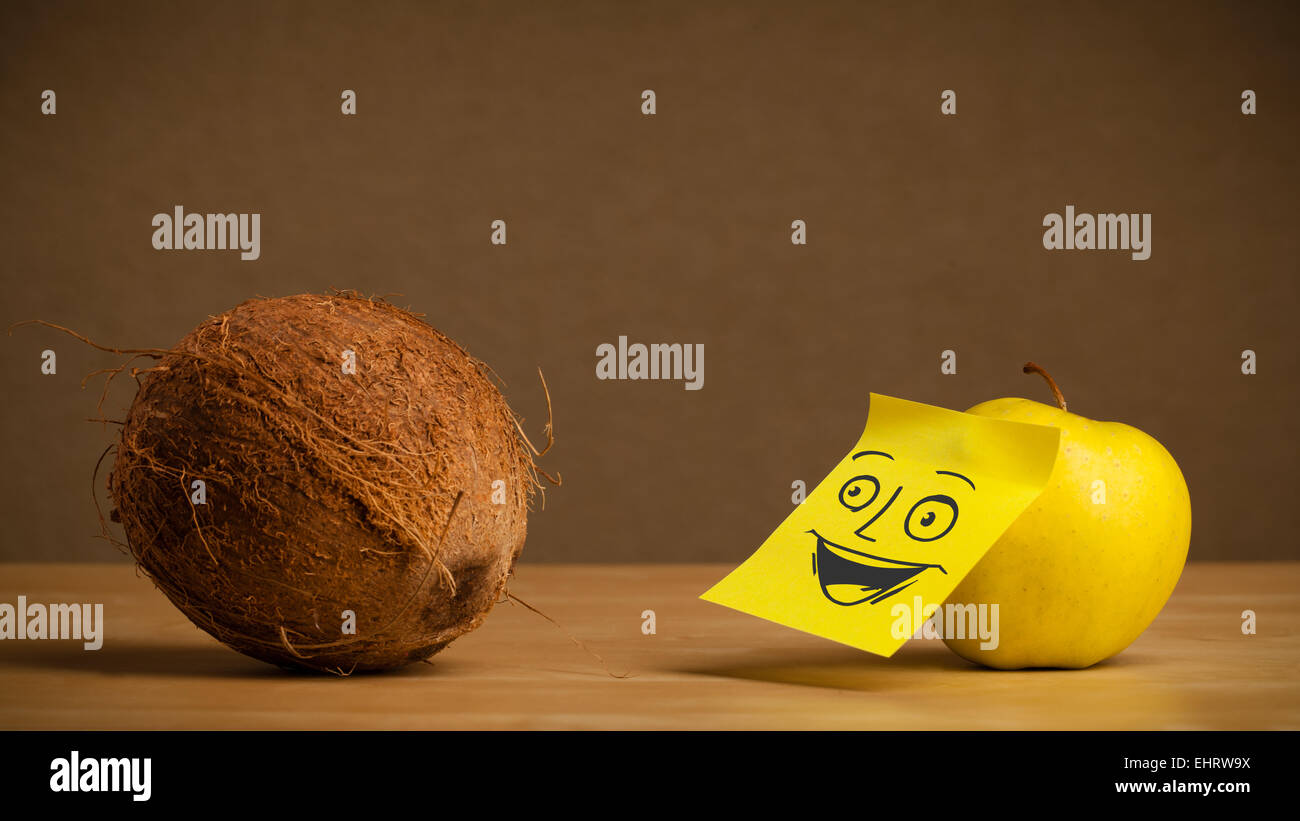 Apple with post-it note smiling at coconut Stock Photo - Alamy
