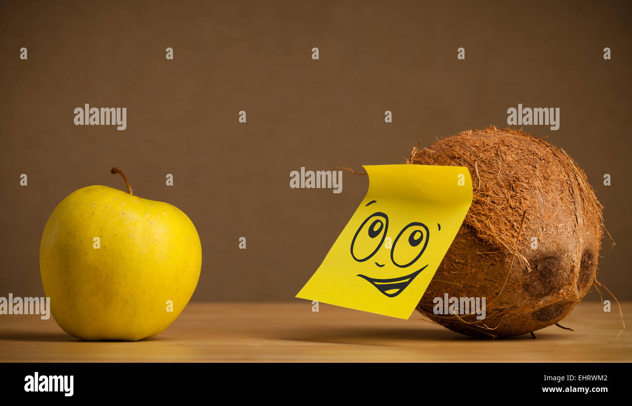 Coconut with post-it note looking at apple Stock Photo - Alamy